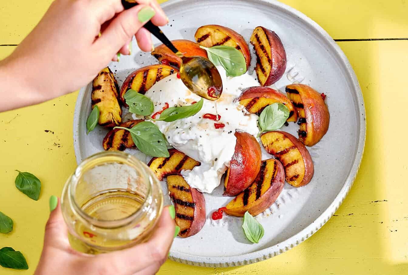 Salade met gegrilde perzik, burrata, basilicum en pittige honing